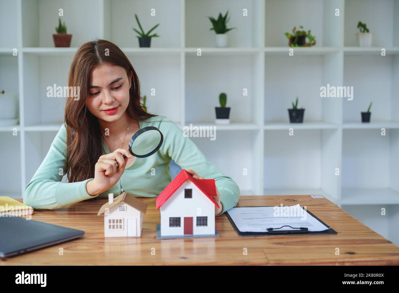 Customer holding a magnifying glass to select a house model, residential inspection concept ...