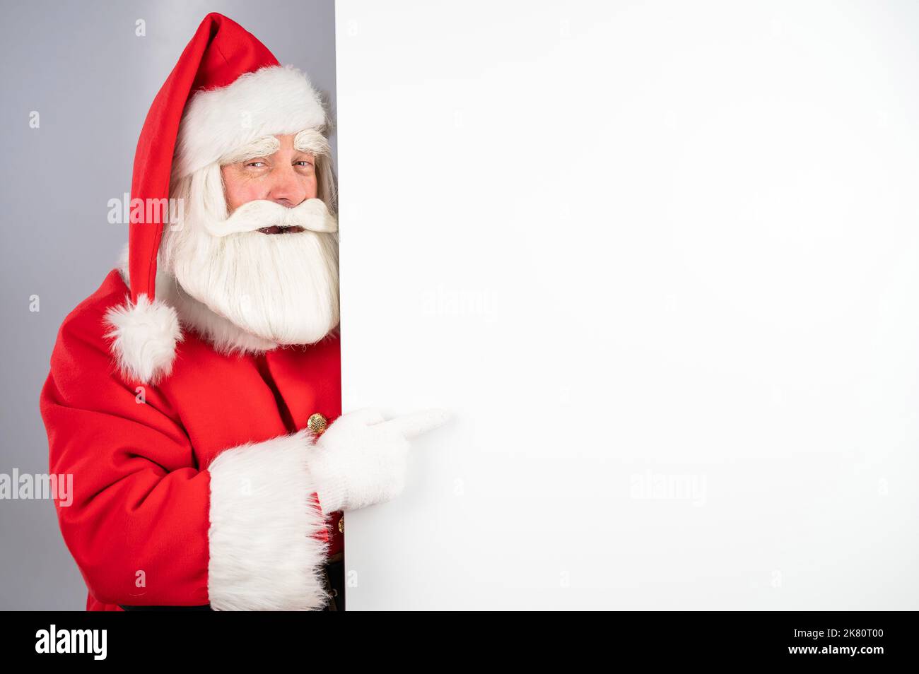 Santa Claus peeks out from behind an ad on a white background. Merry ...