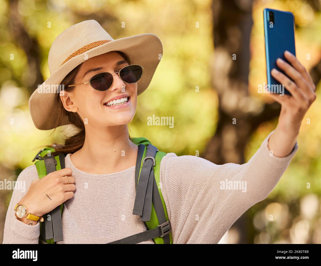 Nature, phone selfie and woman hiking with hat, sunglasses and smile ...