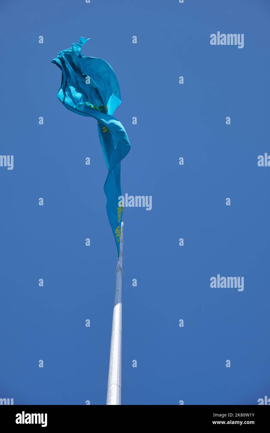 A giant, blue Kazakh flag, proudly flying on a tall flagpole in Central ...