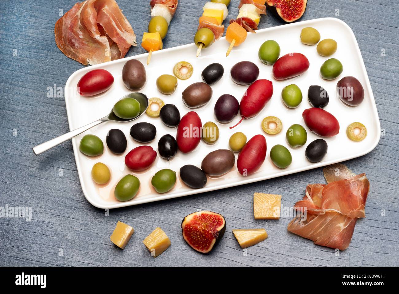 Jamon, cheese, figs and skewers with cheese, olives and jamon on table ...