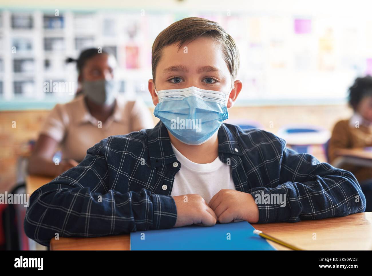 Masks make up the uniform at school. a young boy sitting in his ...