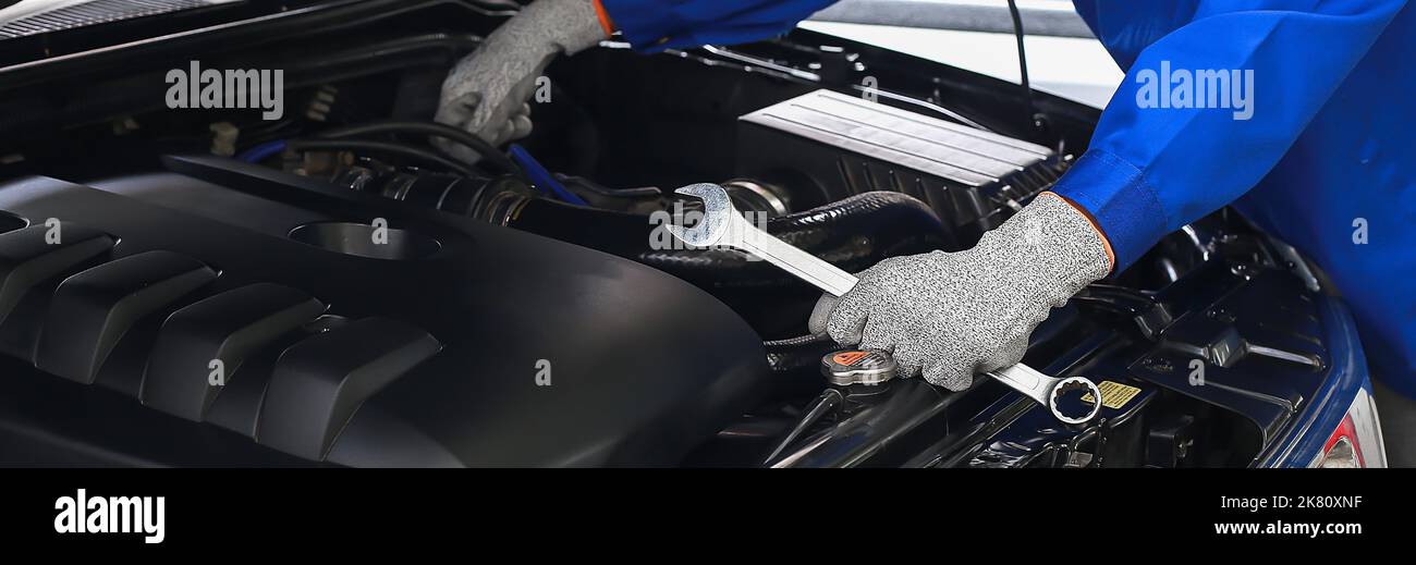 The mechanic works on the engine of the car in the garage, car repair ...