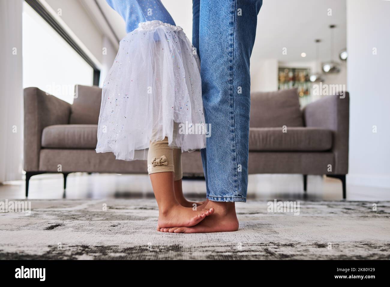 Feet, child and mother teaching a dance ballet movement on the living ...