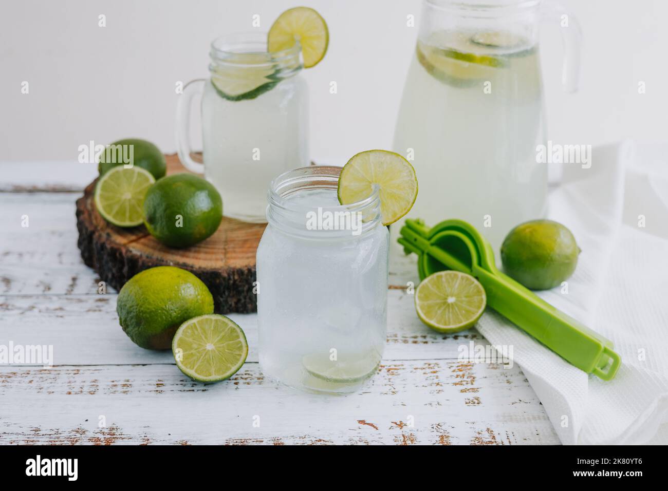 Jar glass of lemonade drink with green lemons or lime on a white ...