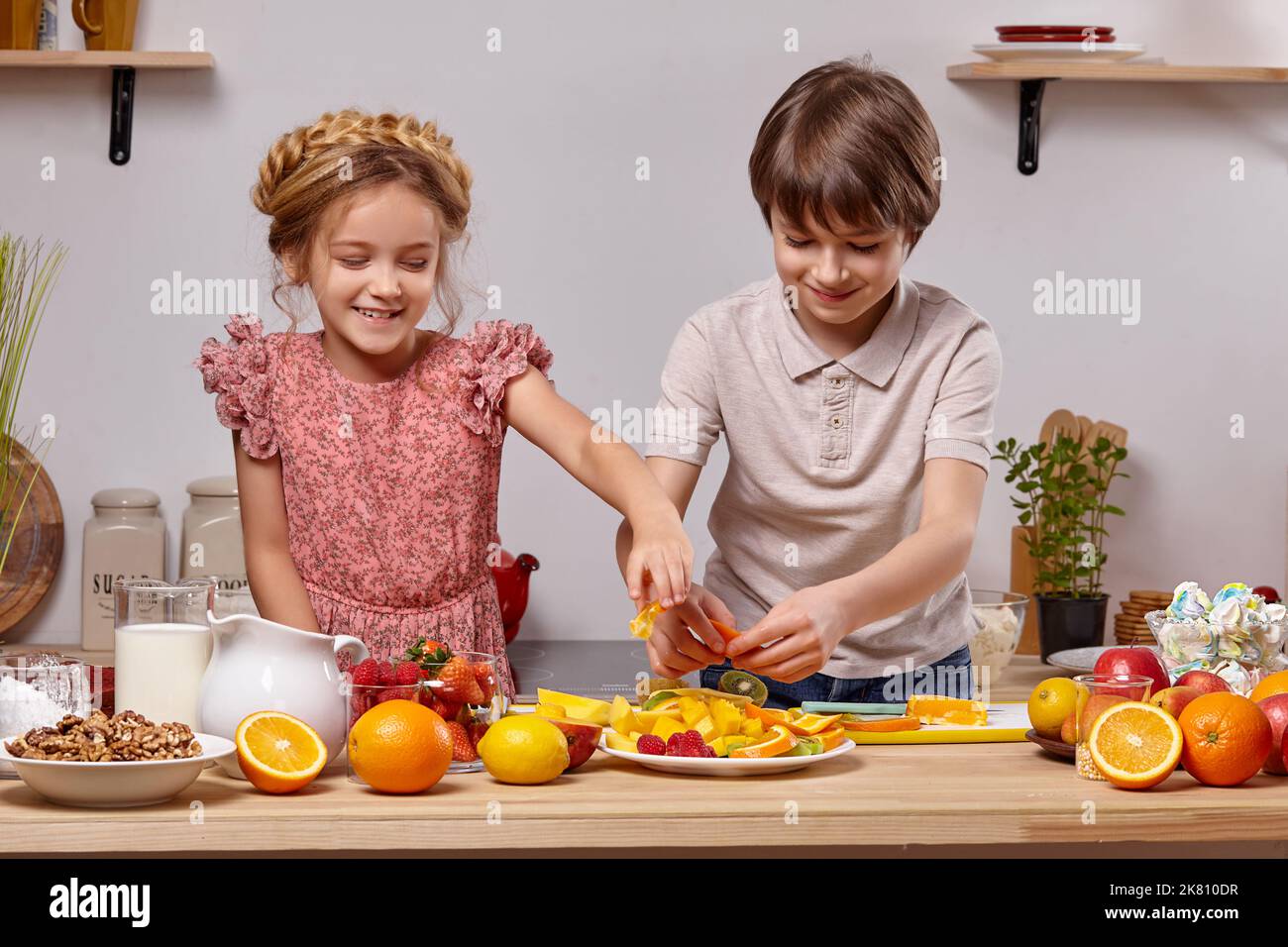 Cute kids are cooking together in a kitchen against a white wall with ...