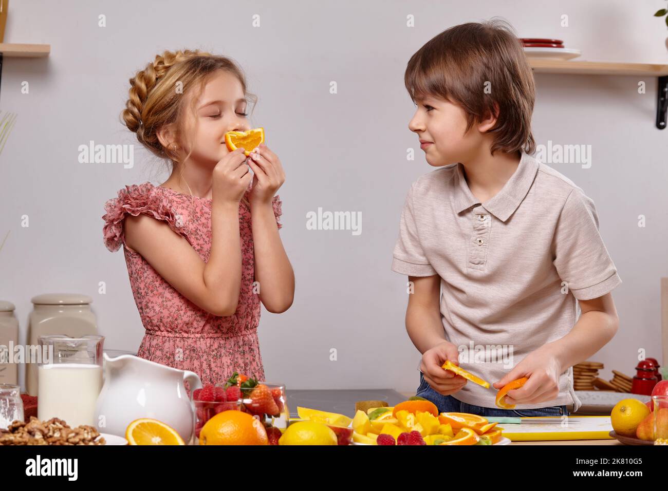 Cute kids are cooking together in a kitchen against a white wall with ...