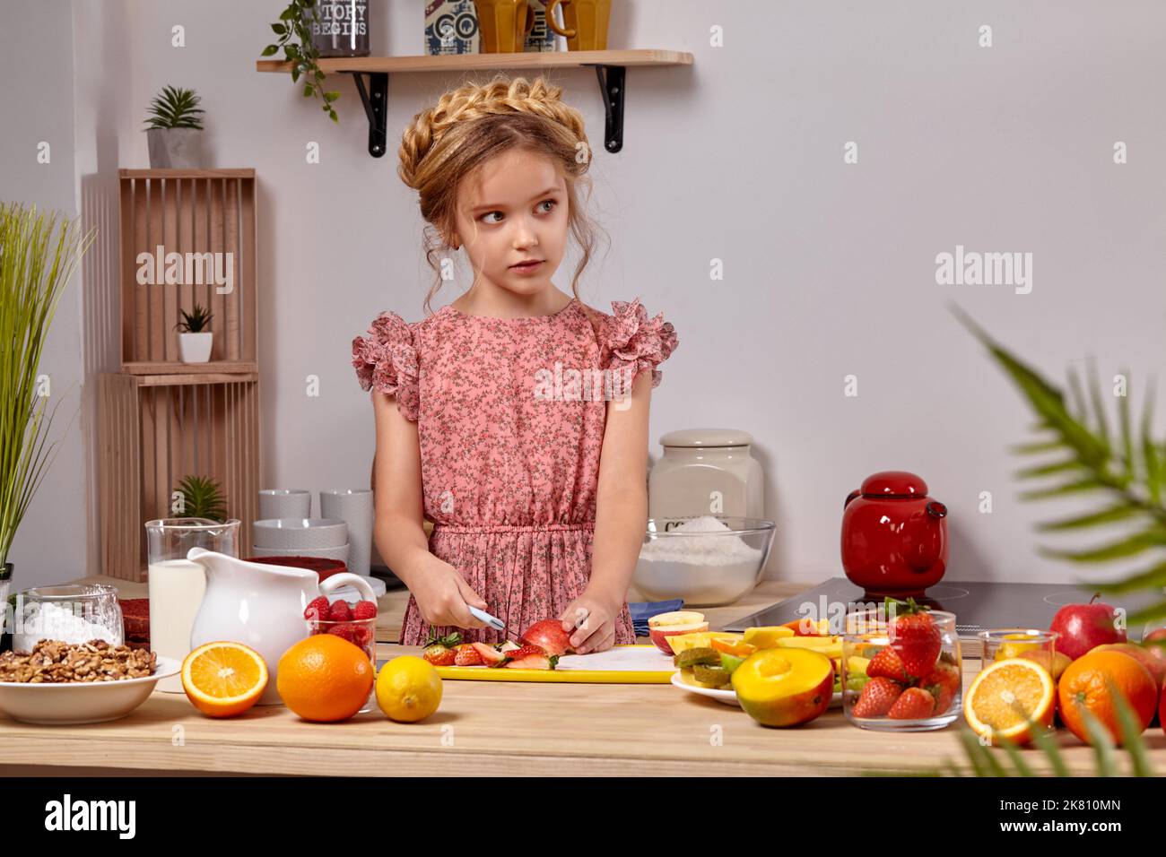 Cute beautiful girl with a modern hairstyle is cooking at a kitchen ...