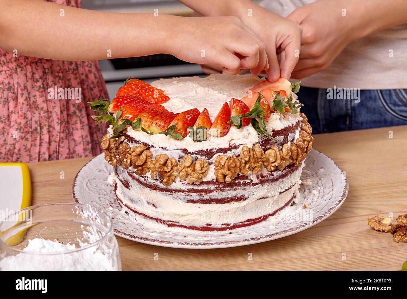 Little friends are making a cake together at a kitchen against a white ...