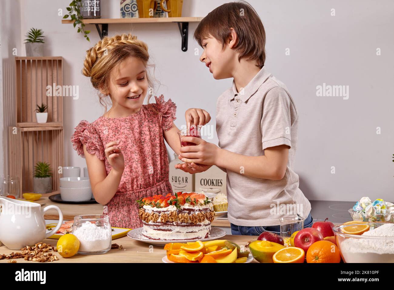 Little friends are making a cake together at a kitchen against a white ...