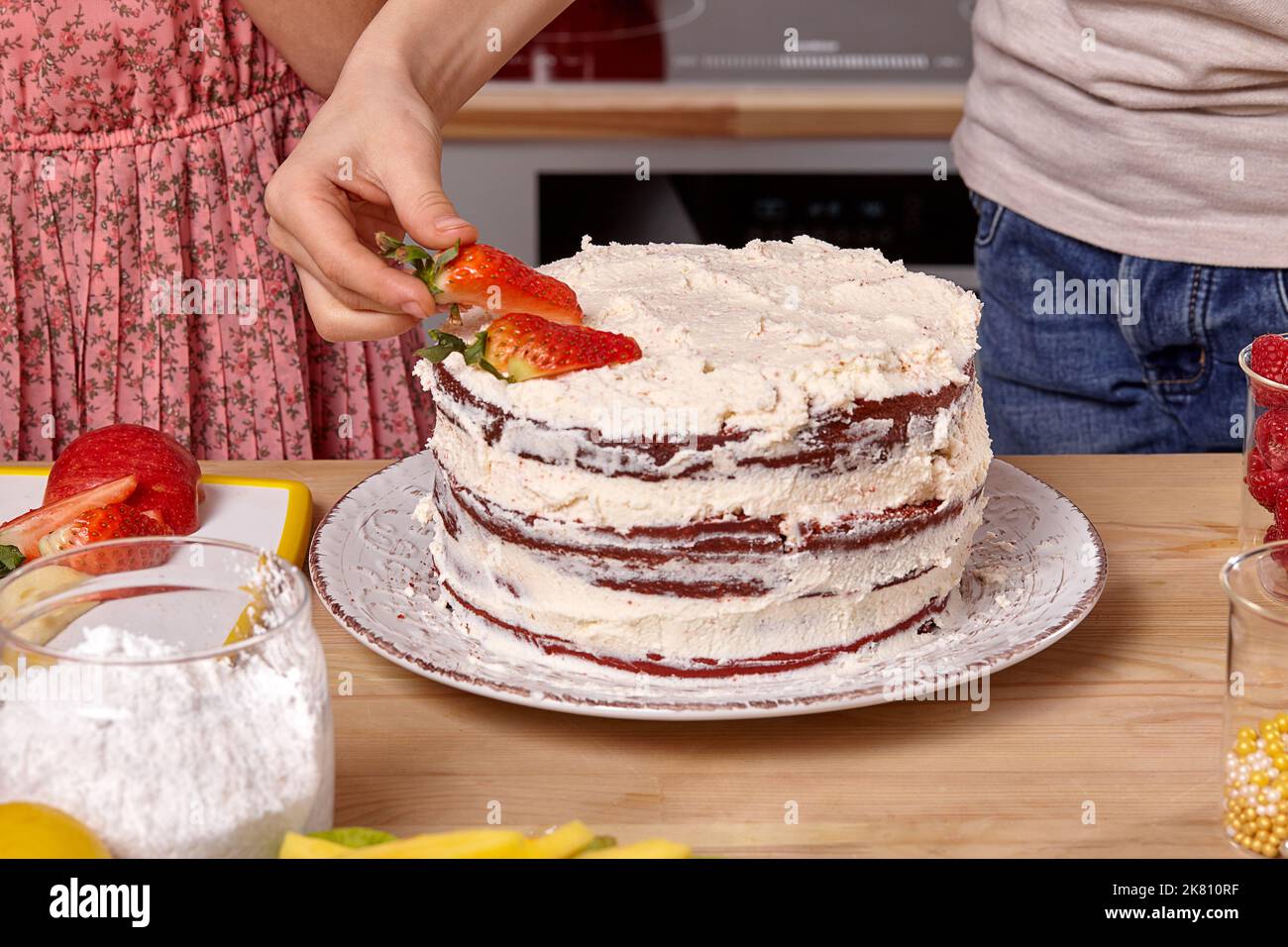 Little friends are making a cake together at a kitchen against a white ...