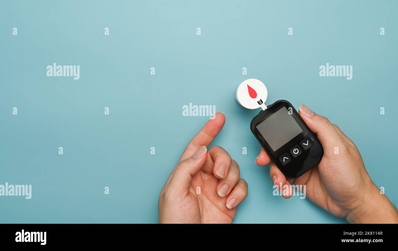 Man with red blood drop and glucose meter over blue background ...