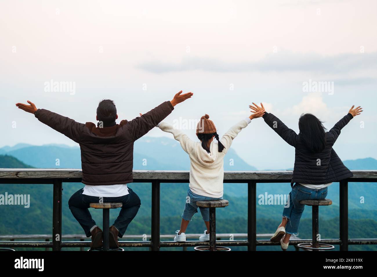 Happy family, featuring father, mother and daughter, raising their arms ...