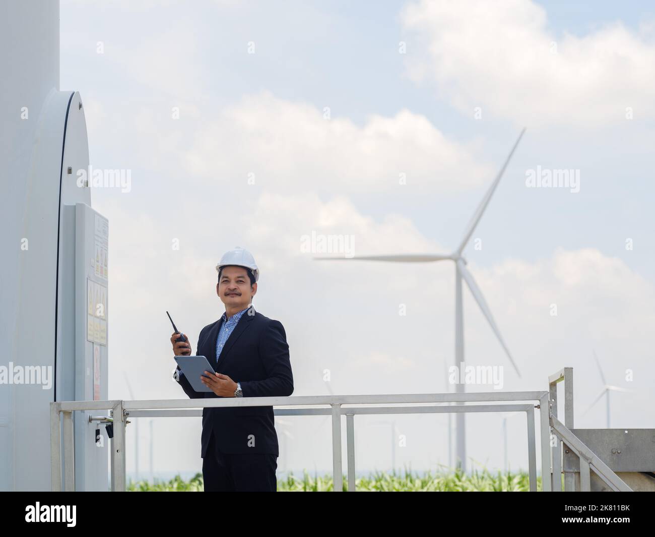Asian engineer manager in a suit is using a tablet to control and ...