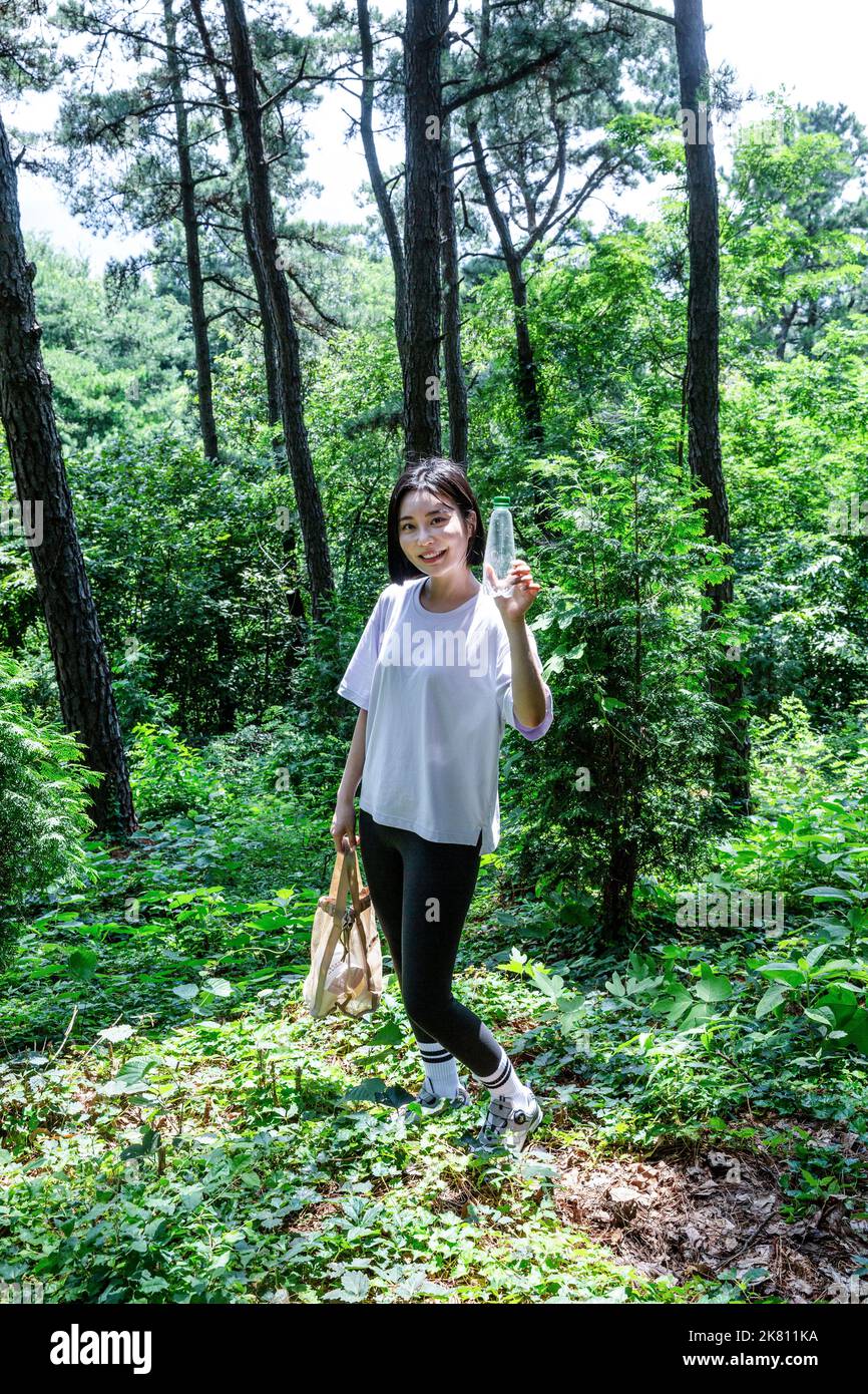 korean young woman hiking and plogging picking up litter, garbage Stock ...