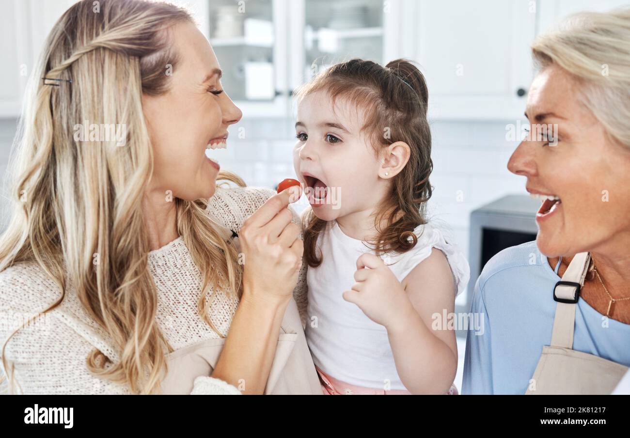 Family, feeding and tomato with a girl and mother eating together in ...