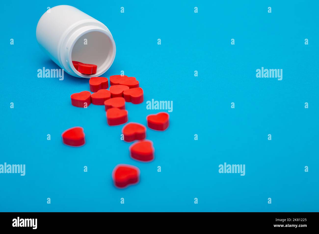 Red heart shaped pills with plastic bottle on blue background.Concept ...