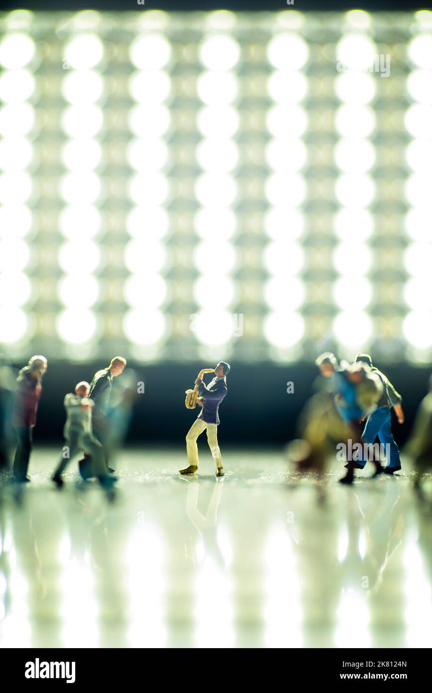 Miniature people toy - Man blowing saxophone on the street among busy ...