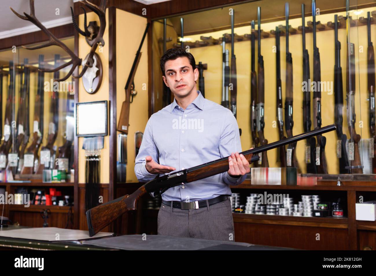 Handsome adult male owner of hunting shop offering rifle Stock Photo ...