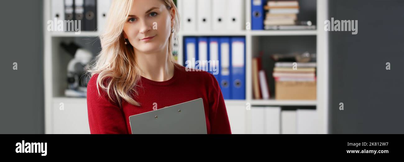 Lovely businesswoman stand with folder in presentable suit, smiling ...