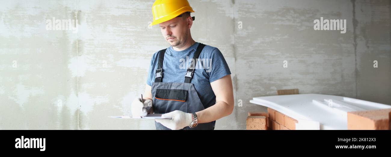 Concentrated male worker hold clipboard and write down needed work ...
