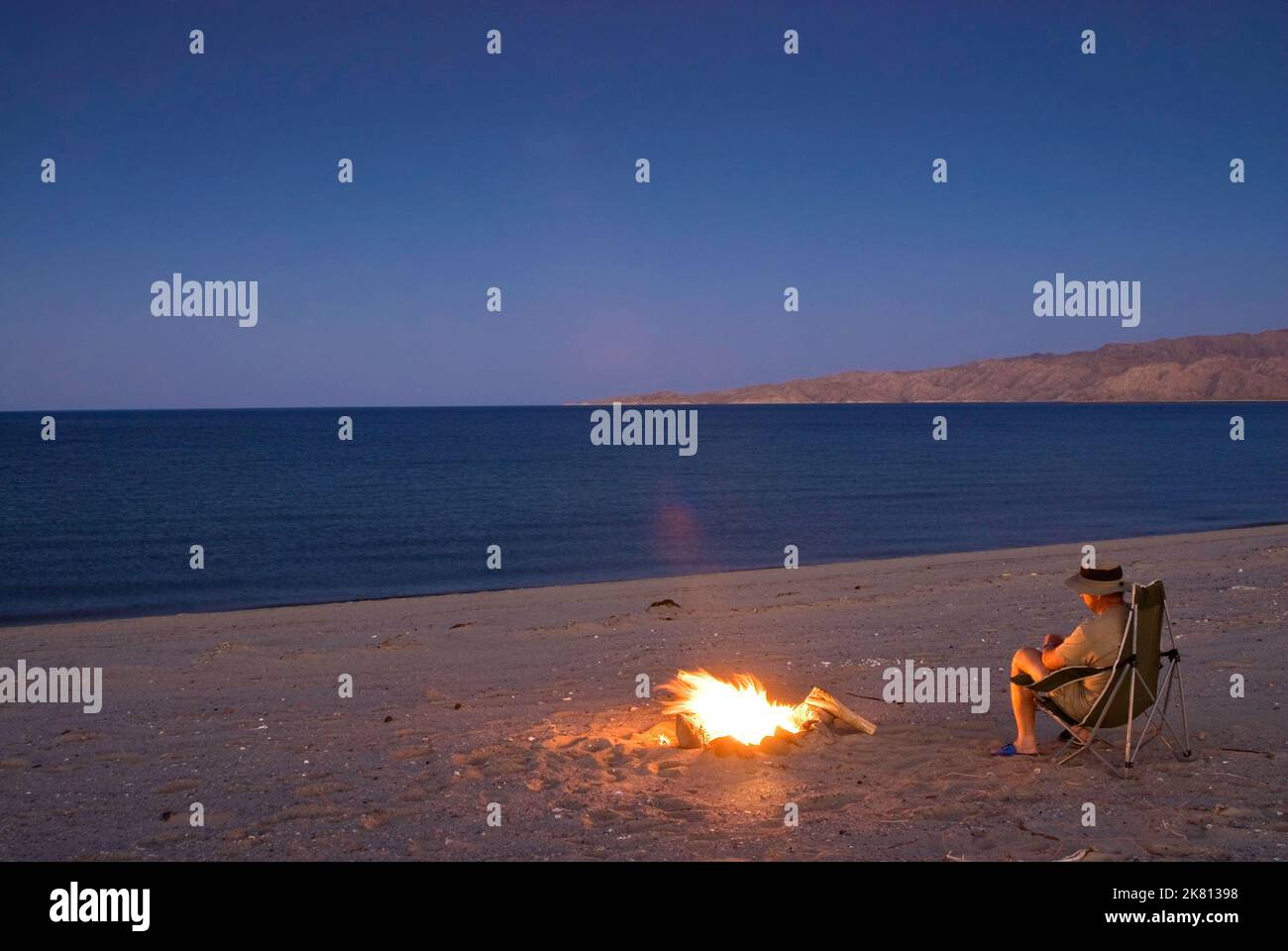 Camper by fire on beach after sunrise at Bahia San Luis Gonzaga at ...