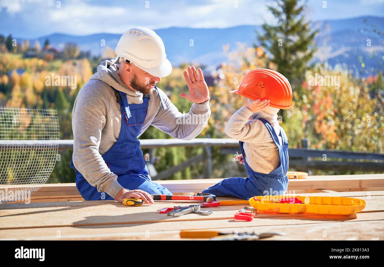 Father with toddler son building wooden frame house. Male builder ...