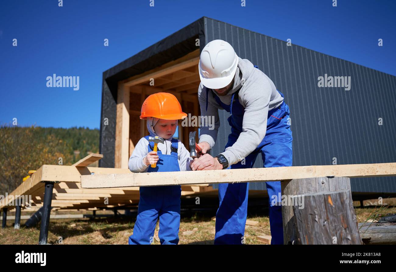 Father with toddler son building wooden frame house. Male builders ...