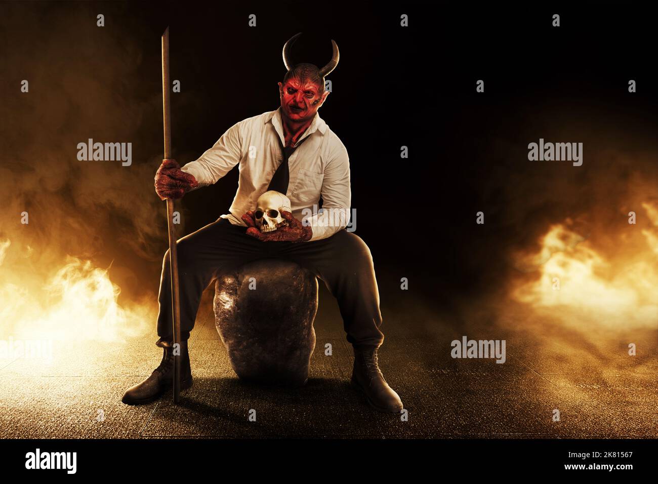 Devilman sitting while holding sticks and a human head skull with fire ...