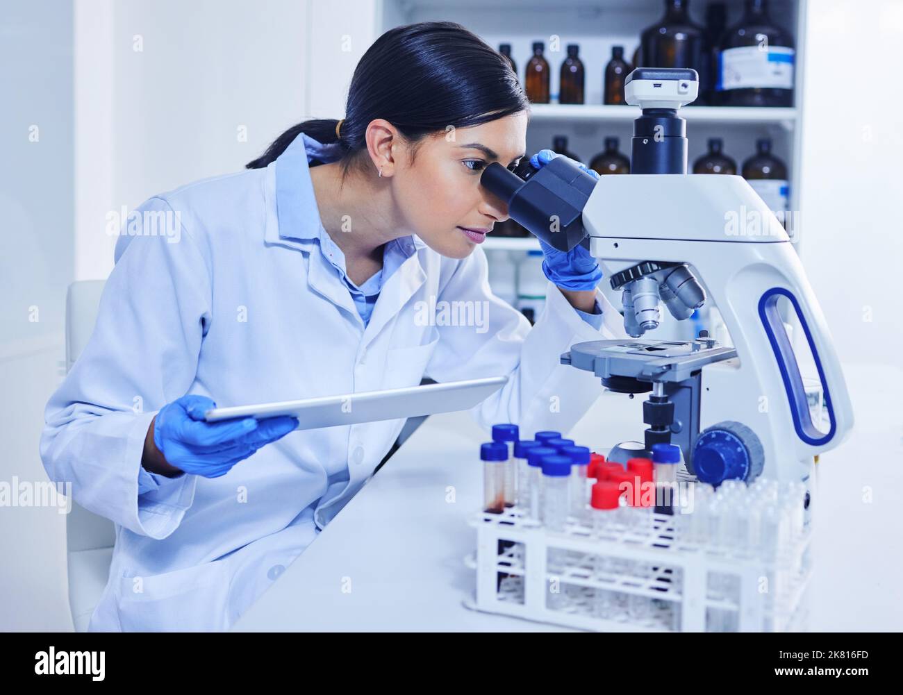 Taking a closer look. an attractive young female scientist working on a ...