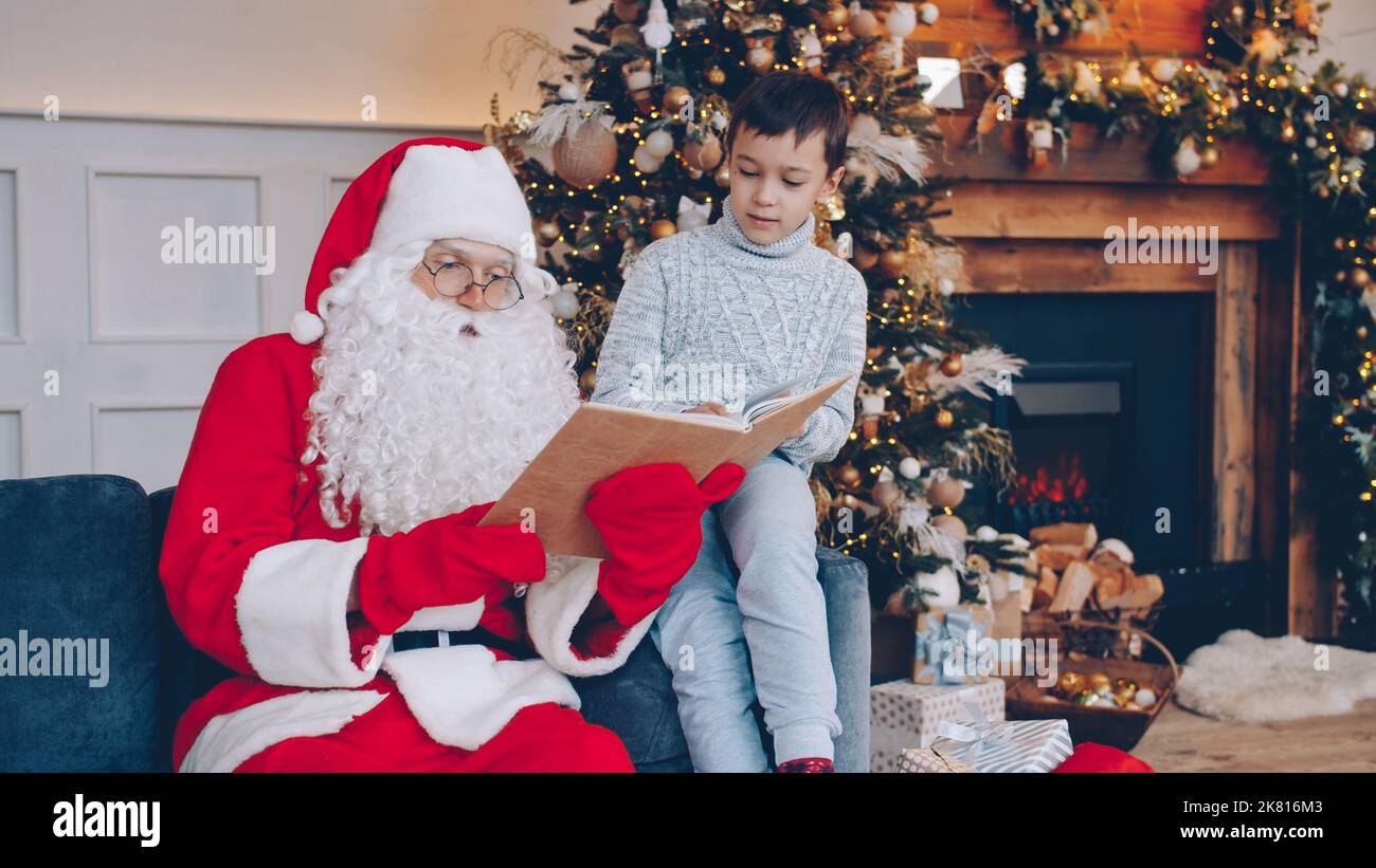 Santa Claus is reading book to happy little boy congratulating child on ...