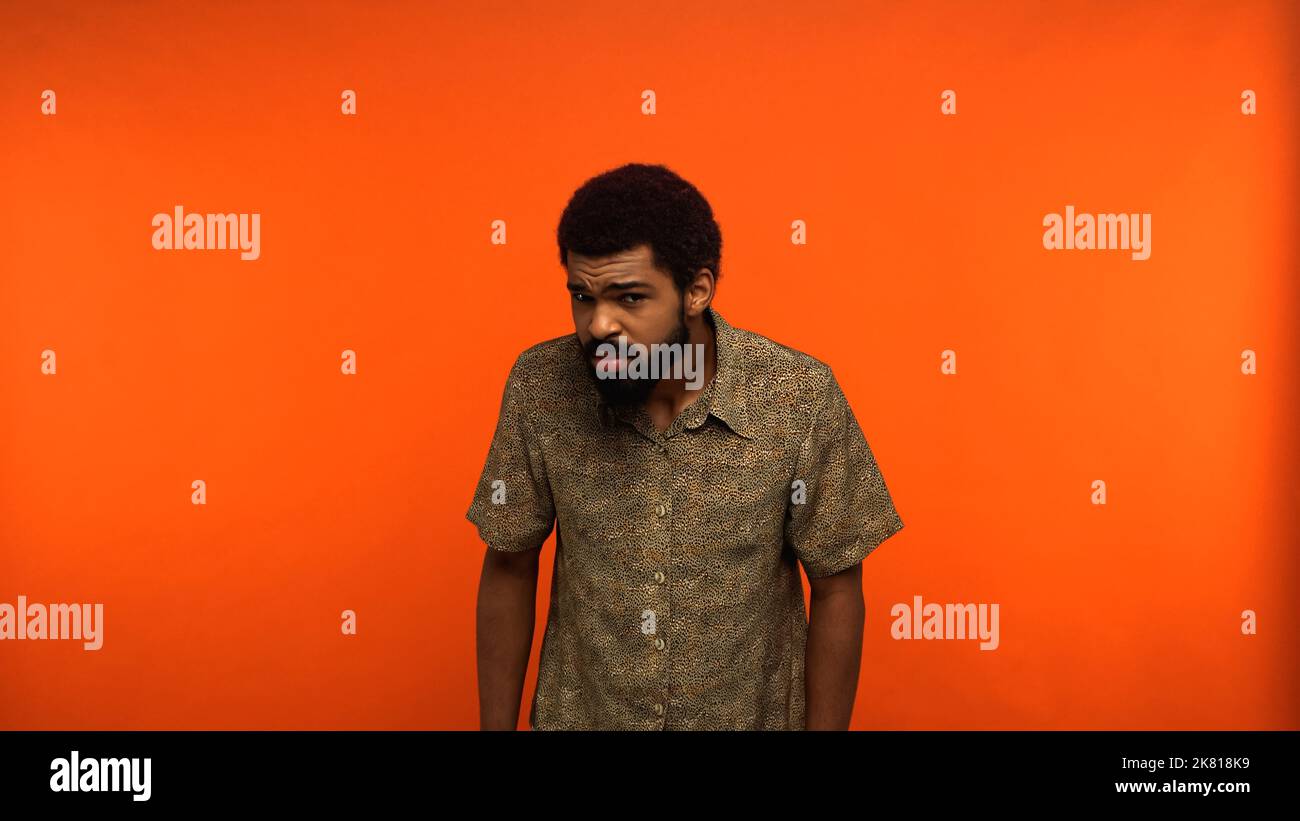 uncertain african american man in shirt looking at camera while ...