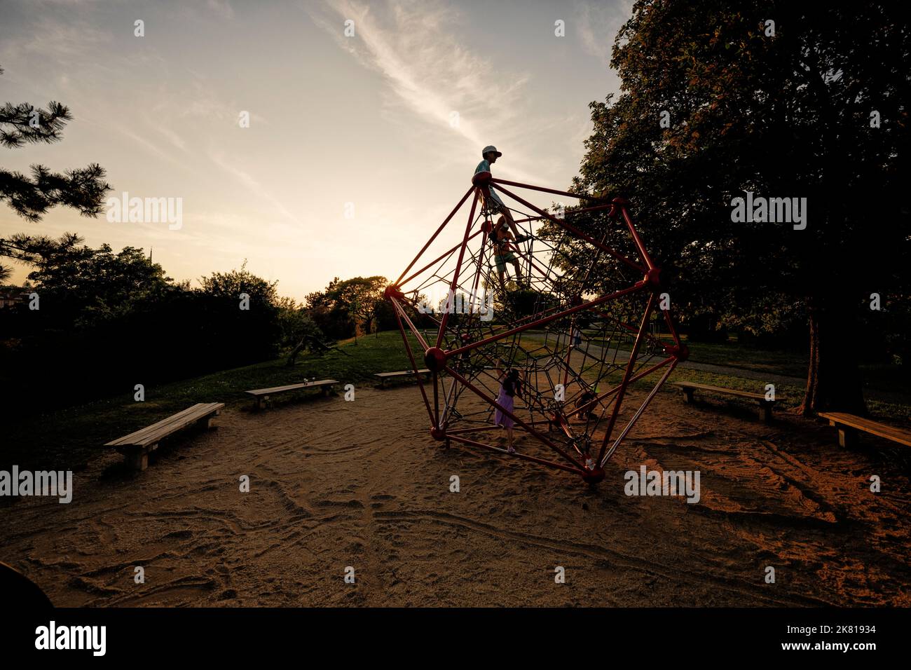 Silhouettes of children play in rope polyhedron climb at playground ...