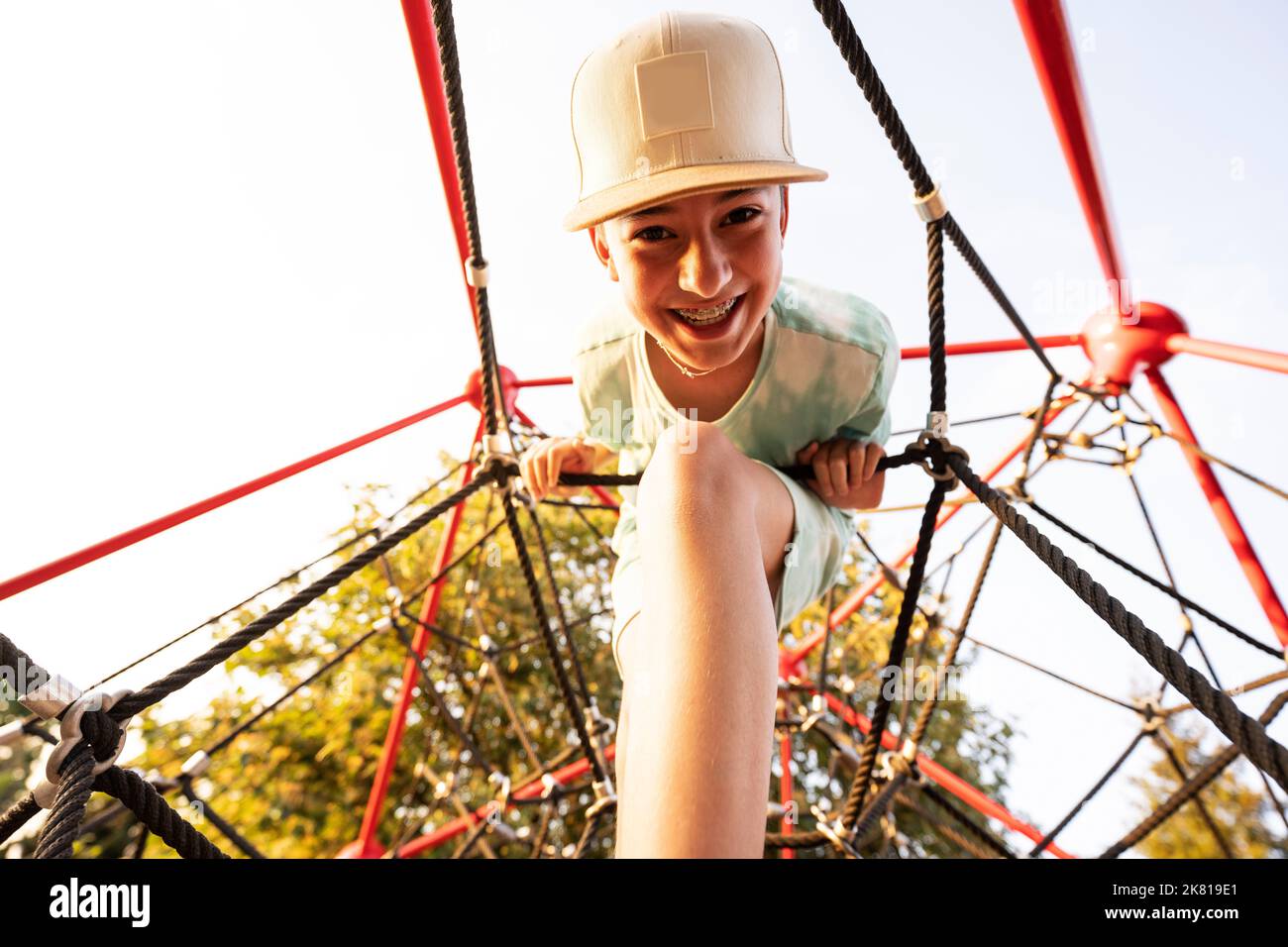 Boy in cap play in rope polyhedron climb at playground outdoor Stock ...