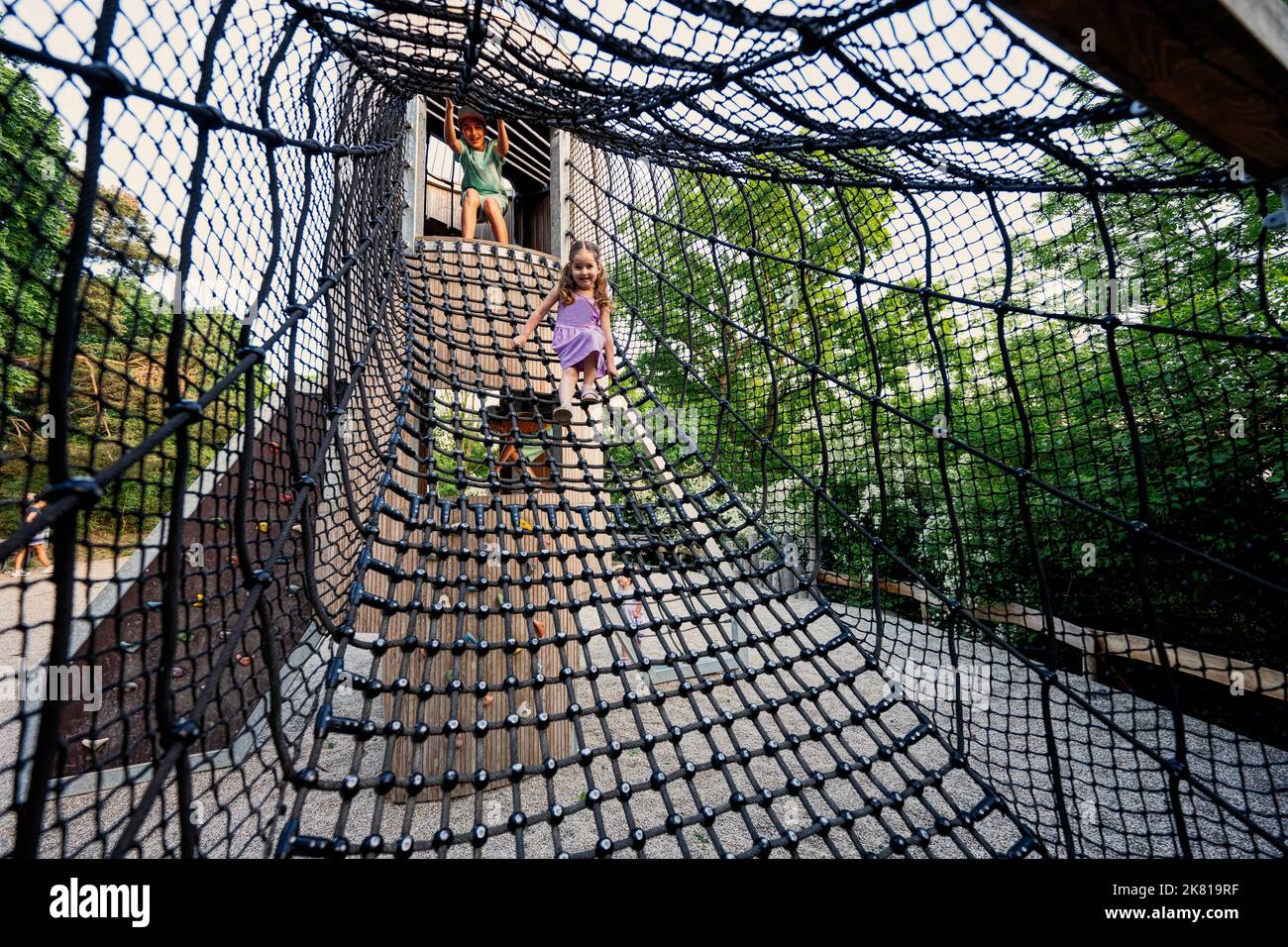Kids playing in rocket slide ropes at children's playground in public ...