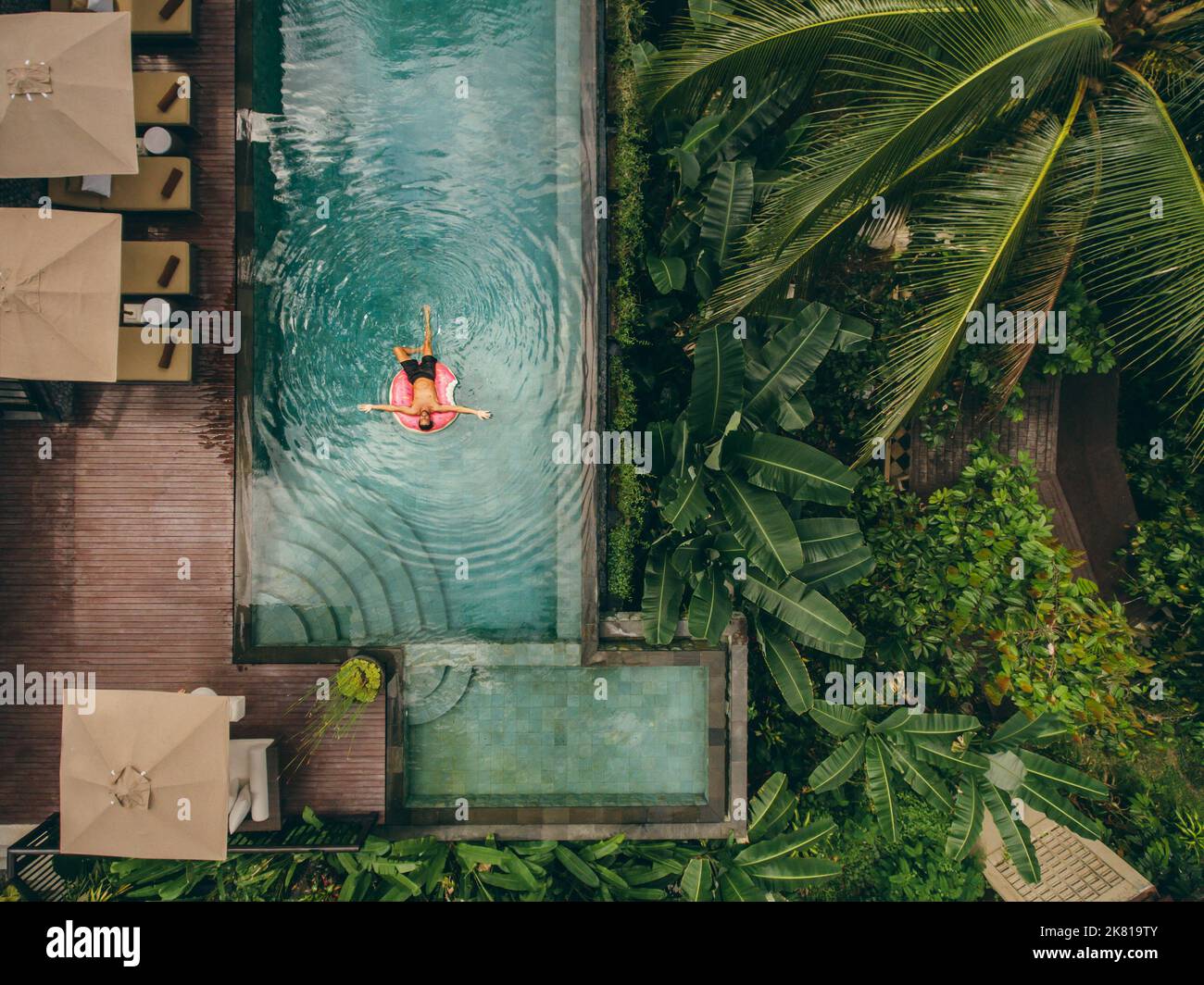 Aerial view of luxury resort with man on inflatable ring in pool. Top ...