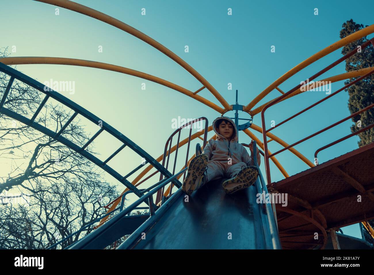 A caucasian kid sliding at playground Stock Photo - Alamy