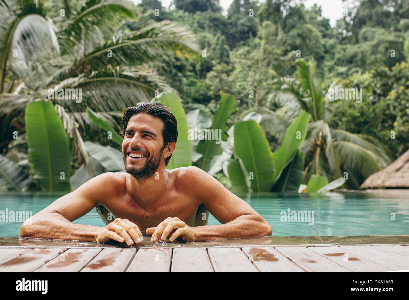 Portrait of smiling young man in swimming pool. Handsome man in pool ...