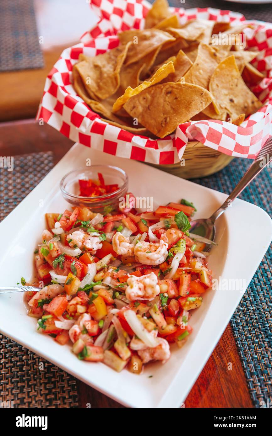 A top view of plate of delicious colorful shrimp Ceviche and basket of ...