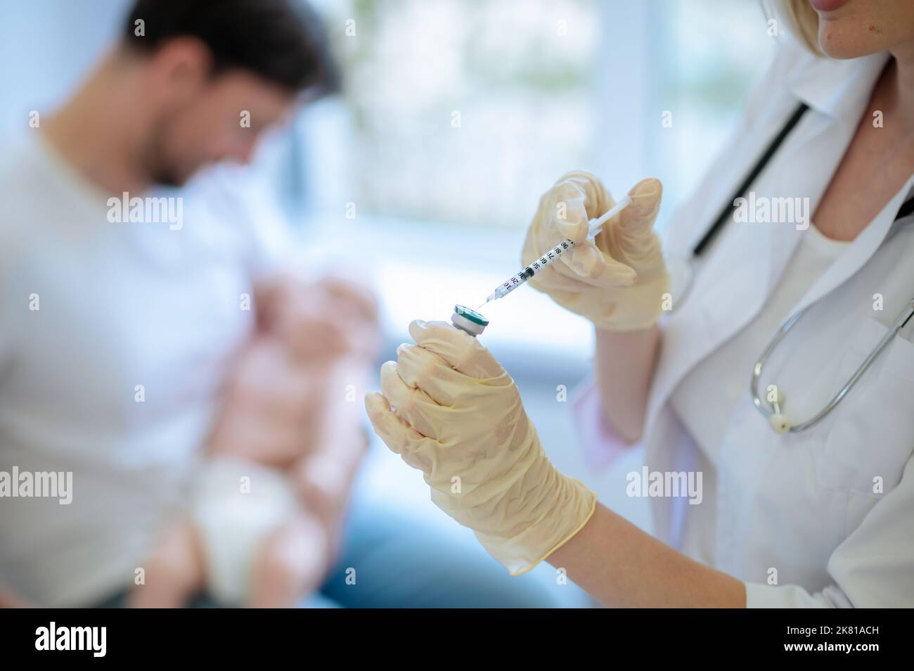 Doctor preparing to administer an injection to a patient Stock Photo ...
