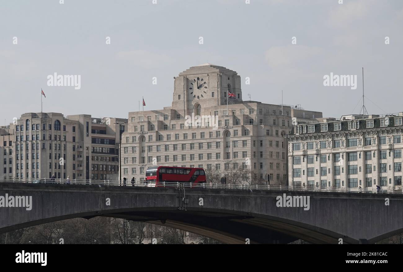 A red bus crossing Waterloo Bridge in front of the former Shell Mex ...