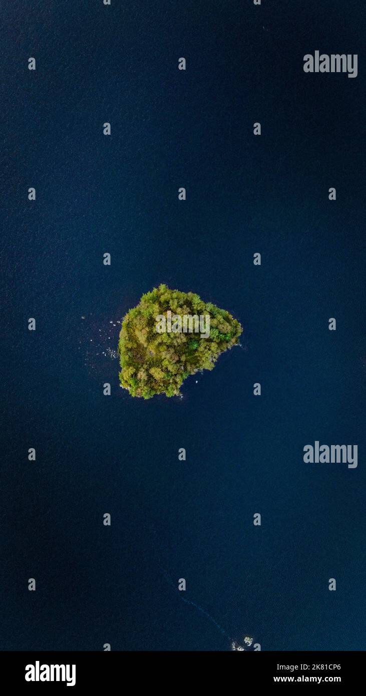A vertical aerial view of a small green island in the middle of the sea ...