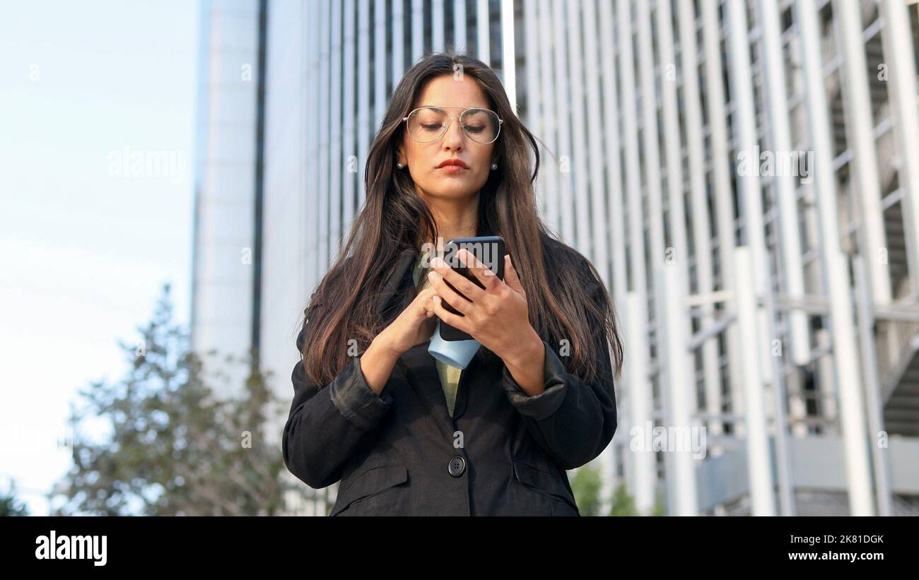 Latin business woman looking at her mobile in a business area Stock ...