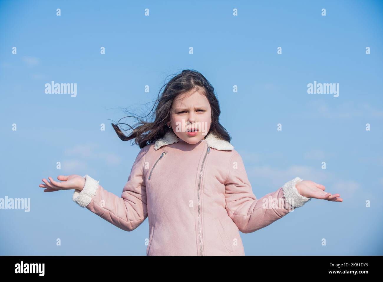 child with confused face presenting product on sky background Stock ...