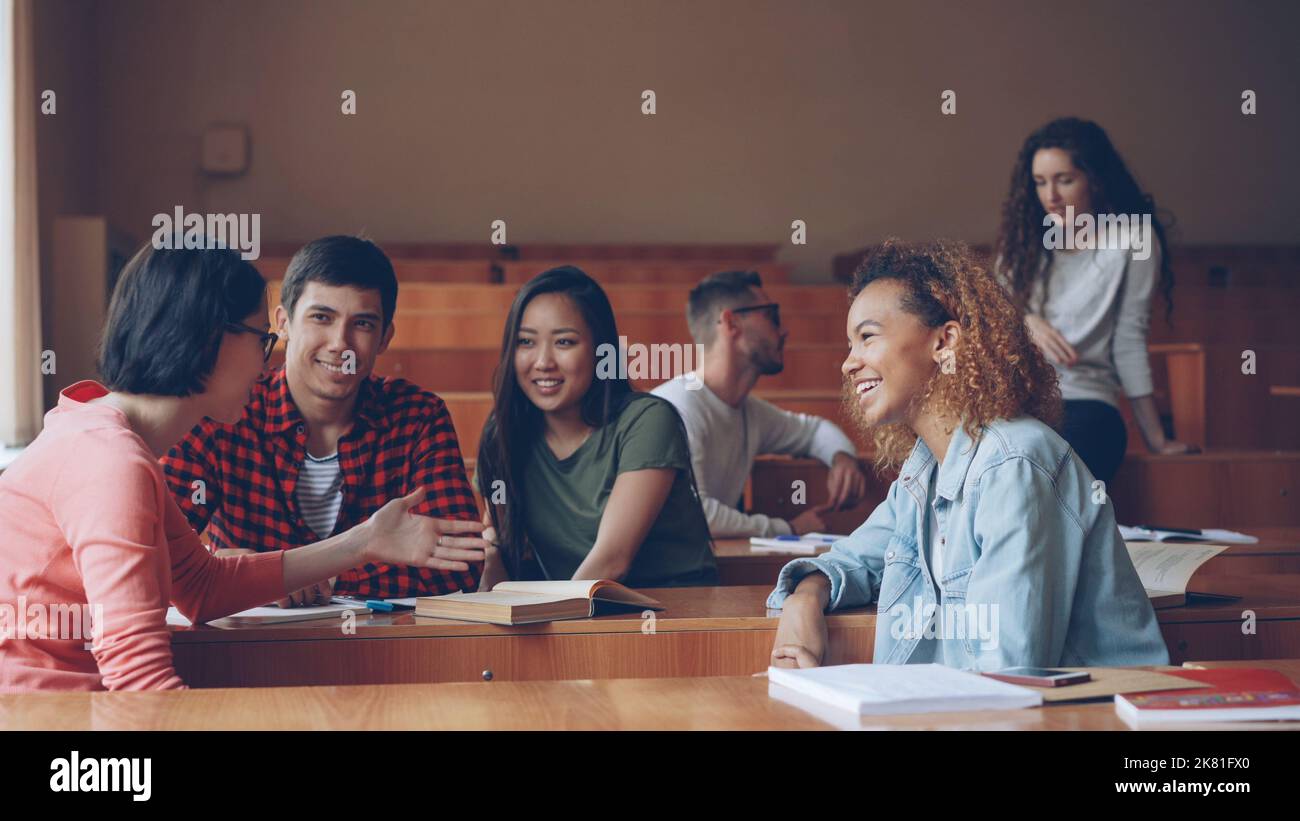 Careless girls and boys are talking and laughing sitting at desks in ...