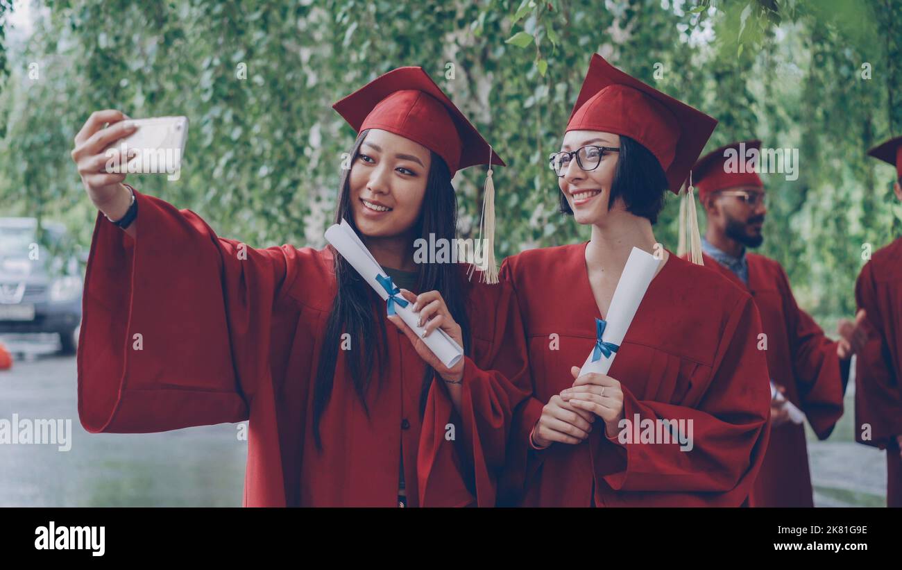 Pretty girls graduating students are taking selfie with diploma scrolls ...
