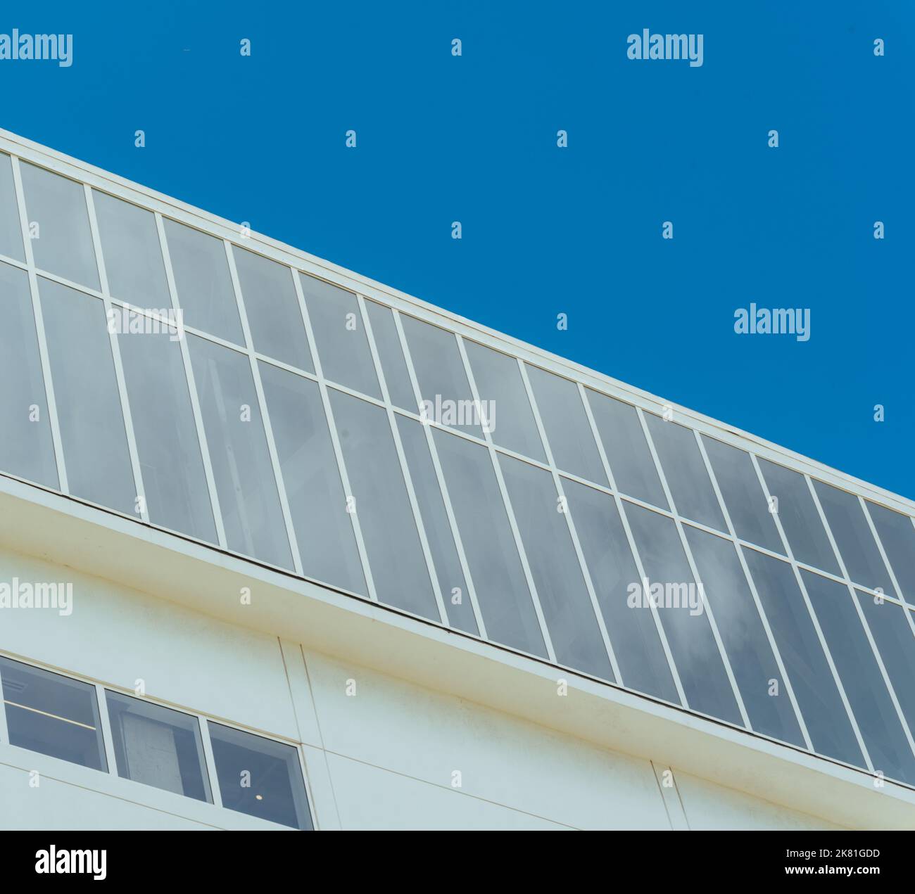 A low-angle shot of glass windows on a building under a clear blue sky ...