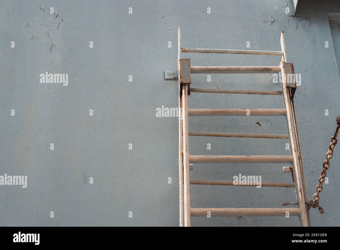 A closeup of a metal rusty ladder leaning against a concrete wall Stock ...