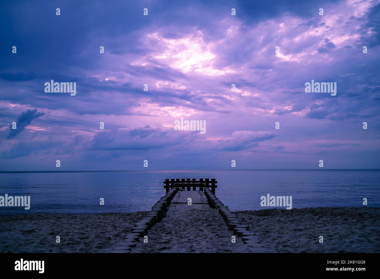 A dock on the beach during the purple sunset Stock Photo - Alamy