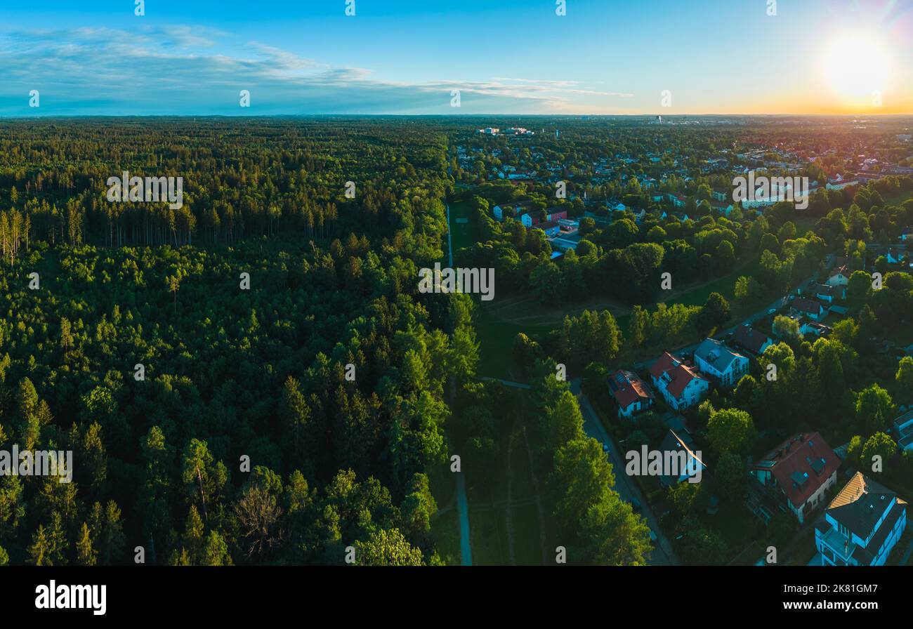 An aerial of Munich's south suburbs with green trees and clear sky ...
